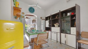 Uma cozinha com mesa de jantar, cadeiras, geladeira, armários e um ventilador de teto.
