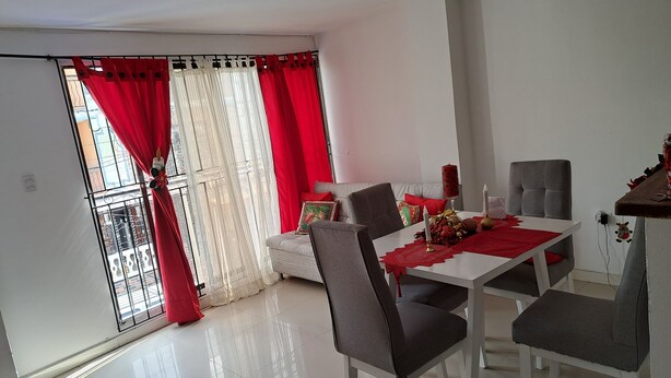 Uma sala de jantar com uma mesa branca, quatro cadeiras cinzentas e detalhes vermelhos.