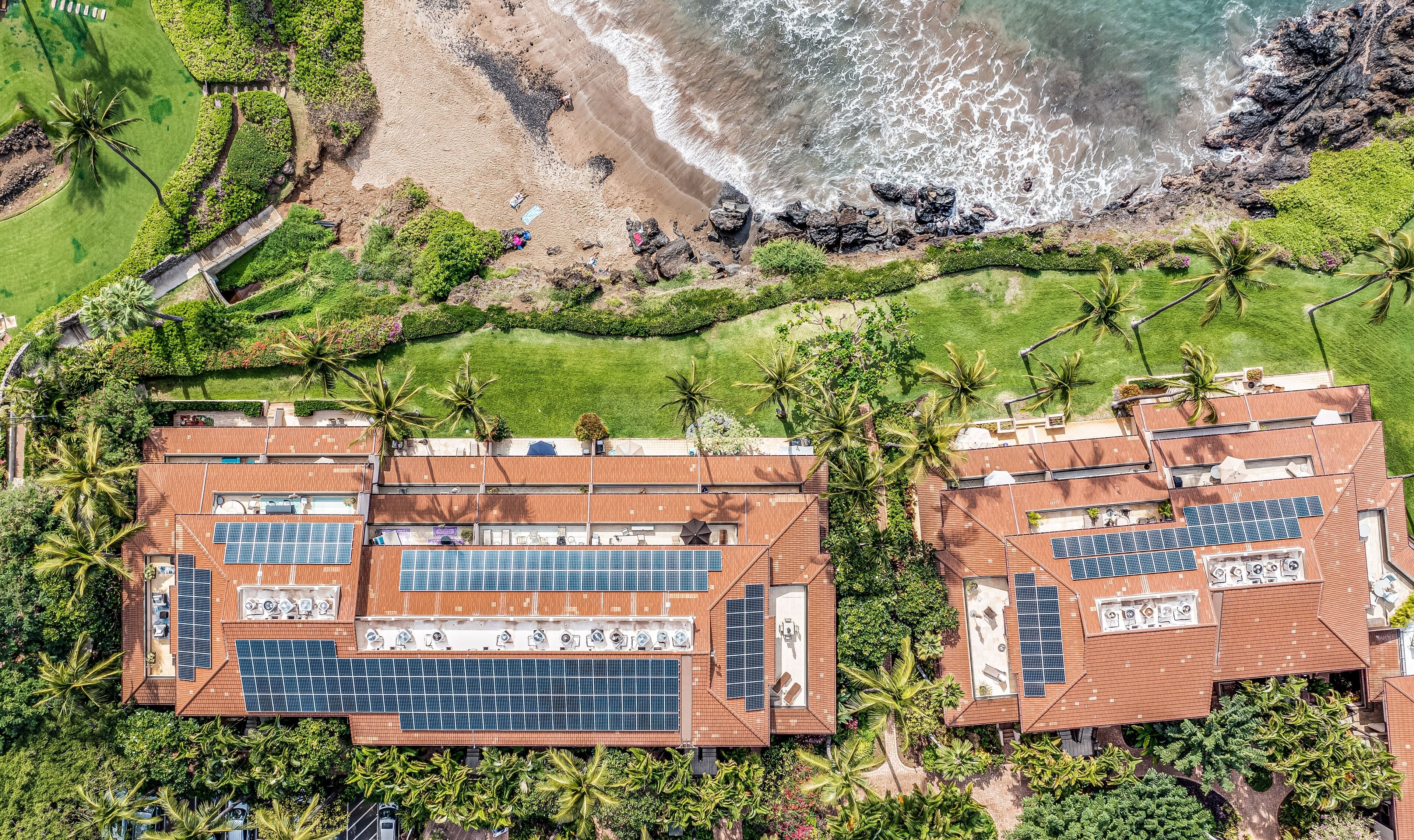 Resort com vários edifícios, painéis solares e uma praia.
