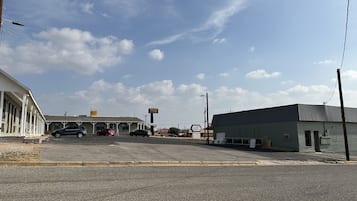 Um motel com área de estacionamento coberta, uma placa de identificação e um edifício com telhado de chapa metálica.