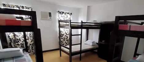 Um quarto com beliches, uma escrivaninha e uma cadeira.