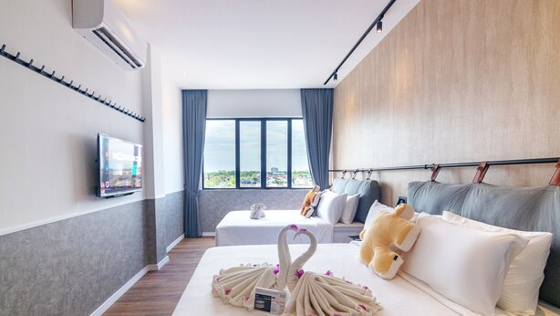 Quarto de hotel com uma cama grande, uma televisão na parede e vista para a cidade pela janela.