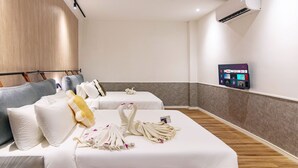 Quarto de hotel com duas camas, um sofá, ar condicionado fixado na parede e painel de controle.
