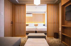 Quarto de hotel com cama, mesas de cabeceira, televisão, lixeira e guarda-roupa de madeira.
