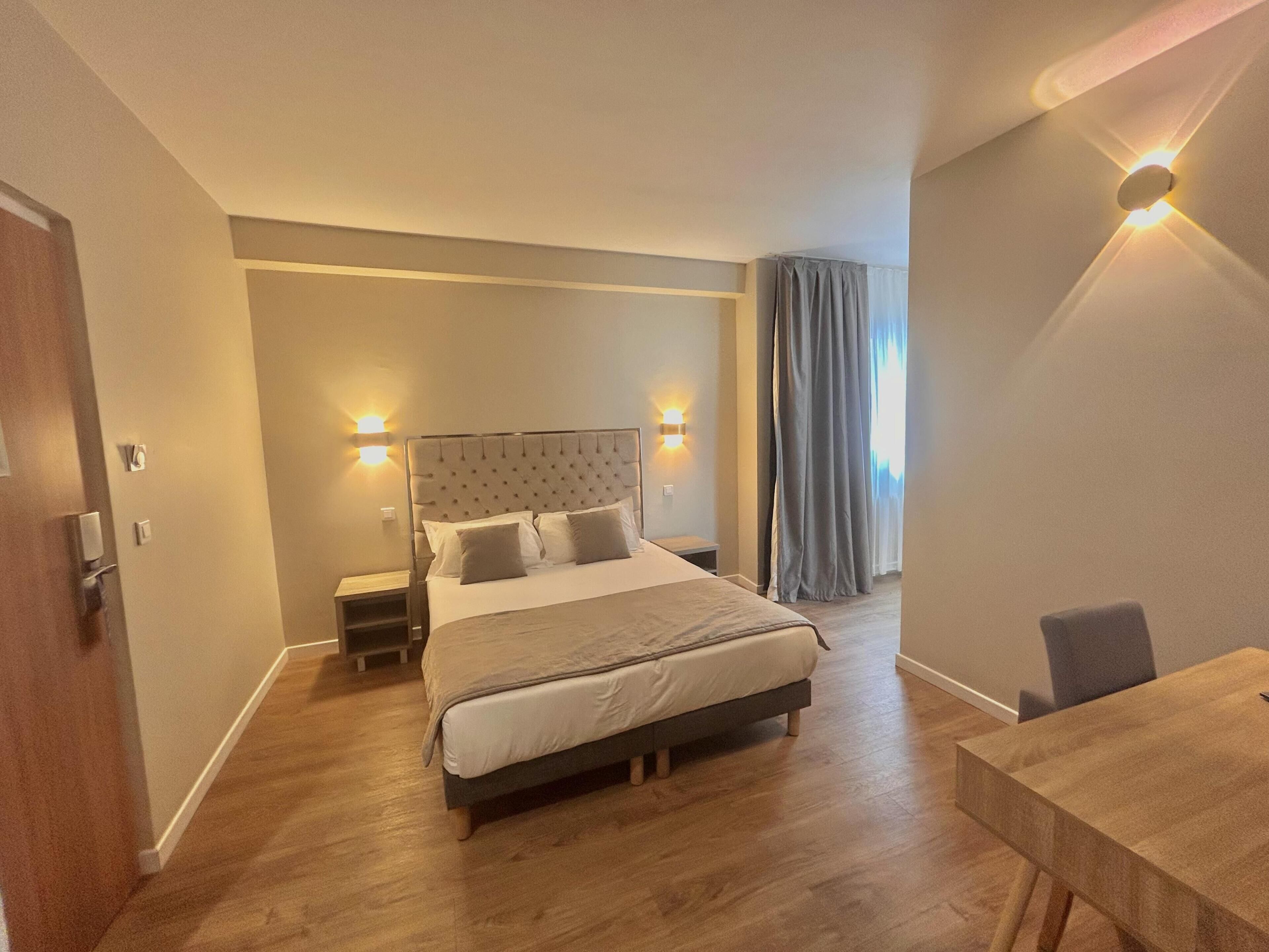 Quarto com cama, mesas de cabeceira, escrivaninha e uma cadeira.