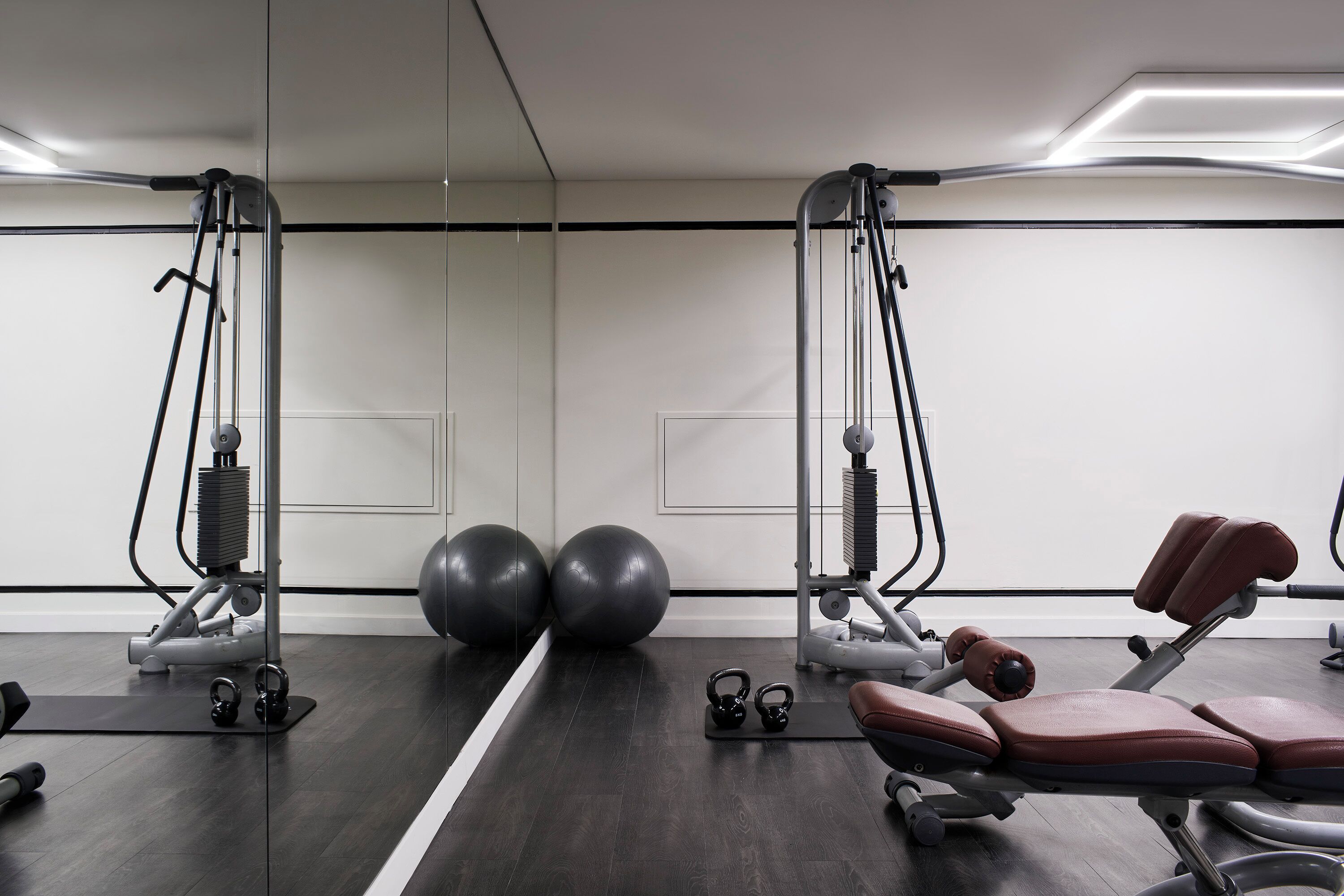 Uma academia moderna com equipamentos de exercícios, uma máquina de remo e uma cadeira de massagem.
