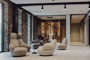Um hall moderno com cadeiras escultóricas exclusivas, parede de pedra e um aparador de madeira.