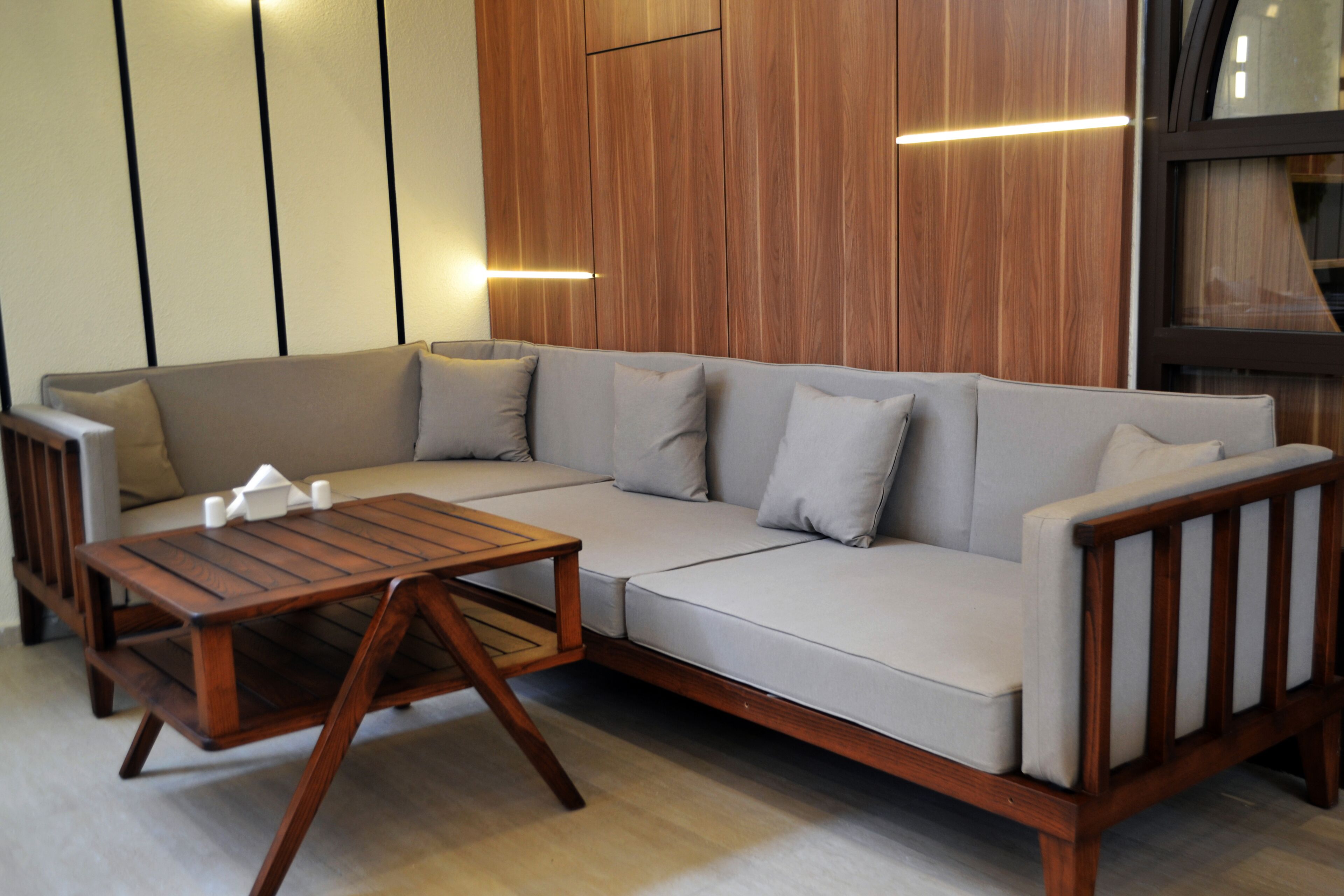 Uma sala de estar moderna com sofá seccional, mesa de centro de madeira e painéis de madeira embutidos.
