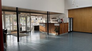 Um hall amplo com uma receção, lambris de madeira e vista para o exterior.