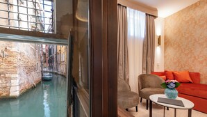 Quarto com vista para um canal estreito, um sofá vermelho, uma poltrona marrom e uma pequena mesa com um vaso.