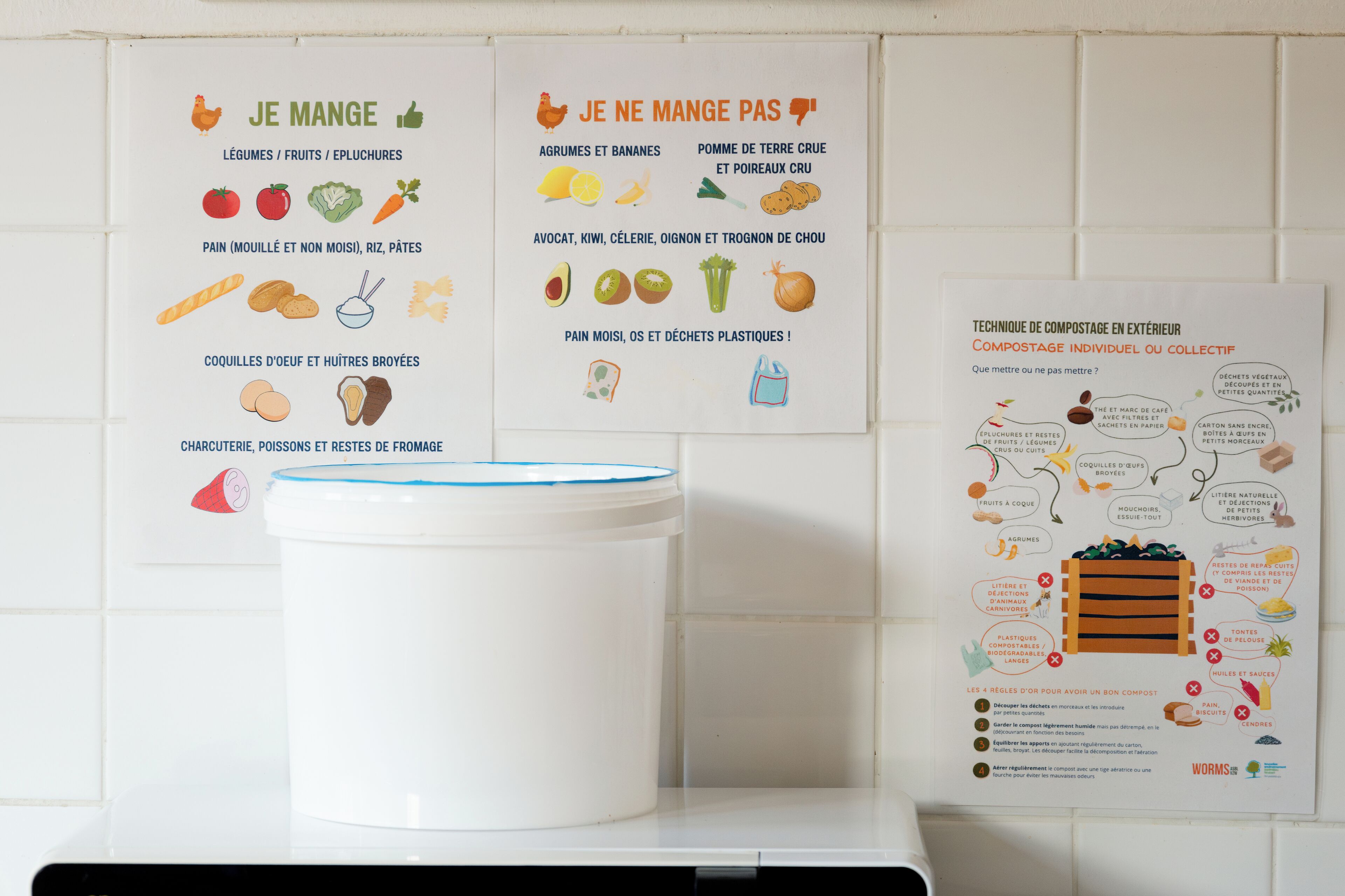 Paredes da cozinha com cartazes educativos sobre desperdício de alimentos e compostagem.