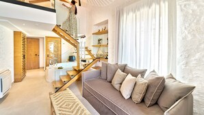 Uma sala de estar moderna com um sofá, uma escada e um espaço para refeições.