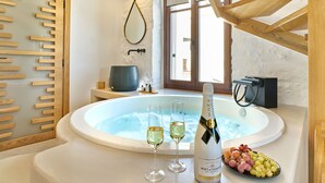 Um quarto de spa com hidromassagem, champanhe e frutas.