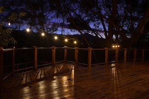Um deck de madeira com luzes de corda e guarda-corpo de madeira.