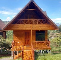 Uma cabana de madeira com varanda, porta e janela.