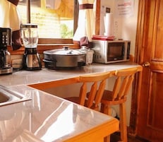 Uma cozinha compacta com pia, liquidificador, micro-ondas e chaleira.