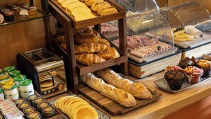 Um buffet de café da manhã com diversos pães, bolos e acompanhamentos.