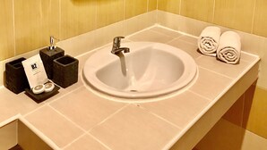 Casa de banho com lavatório, espelho, porta-toalhas e secador de cabelo.