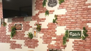 Uma área de refeições com parede de tijolos, uma TV de tela plana e uma mesa com cadeiras.