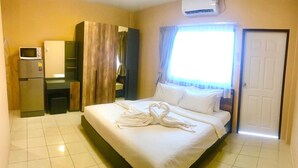 Quarto de hotel com cama, secretária com computador, frigorífico e ar condicionado.