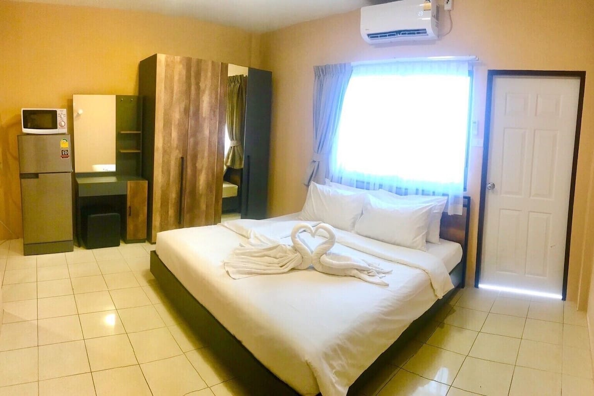 Quarto de hotel com cama, secretária com computador, frigorífico e ar condicionado.