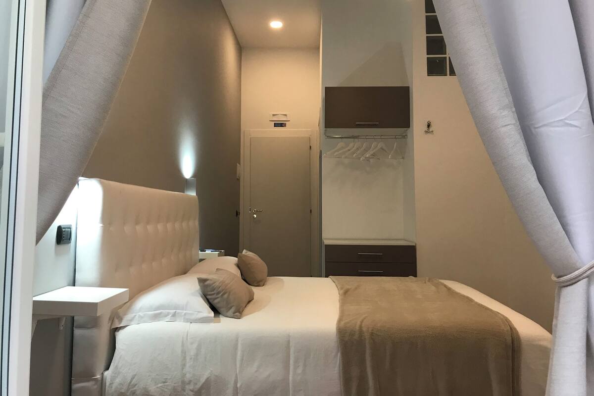 Quarto com cama, mesa de cabeceira e guarda-roupa.