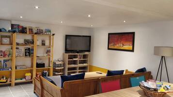 Uma sala de estar com televisão, estante de livros e um quadro na parede.