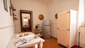 Uma cozinha compacta com uma mesa de jantar, cadeiras, geladeira e uma porta.