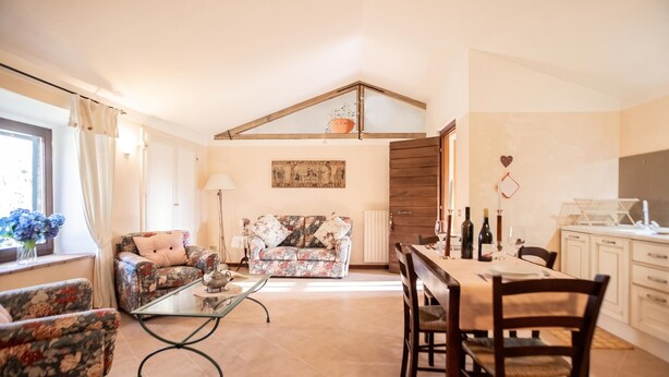 Uma sala de estar acolhedora com um sofá, uma mesa de centro e um espaço de jantar com cadeiras e uma mesa.