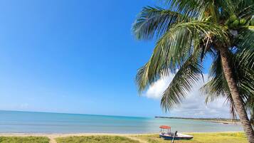 Na praia, praia de areia branca, guarda-sóis de praia, toalhas de praia