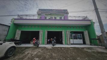 Um edifício com duas garagens abertas, um carro branco estacionado na frente e uma motocicleta dentro de uma delas.