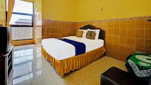 Quarto de hotel com cama, televisão, janela com cortinas e vista para prédios.
