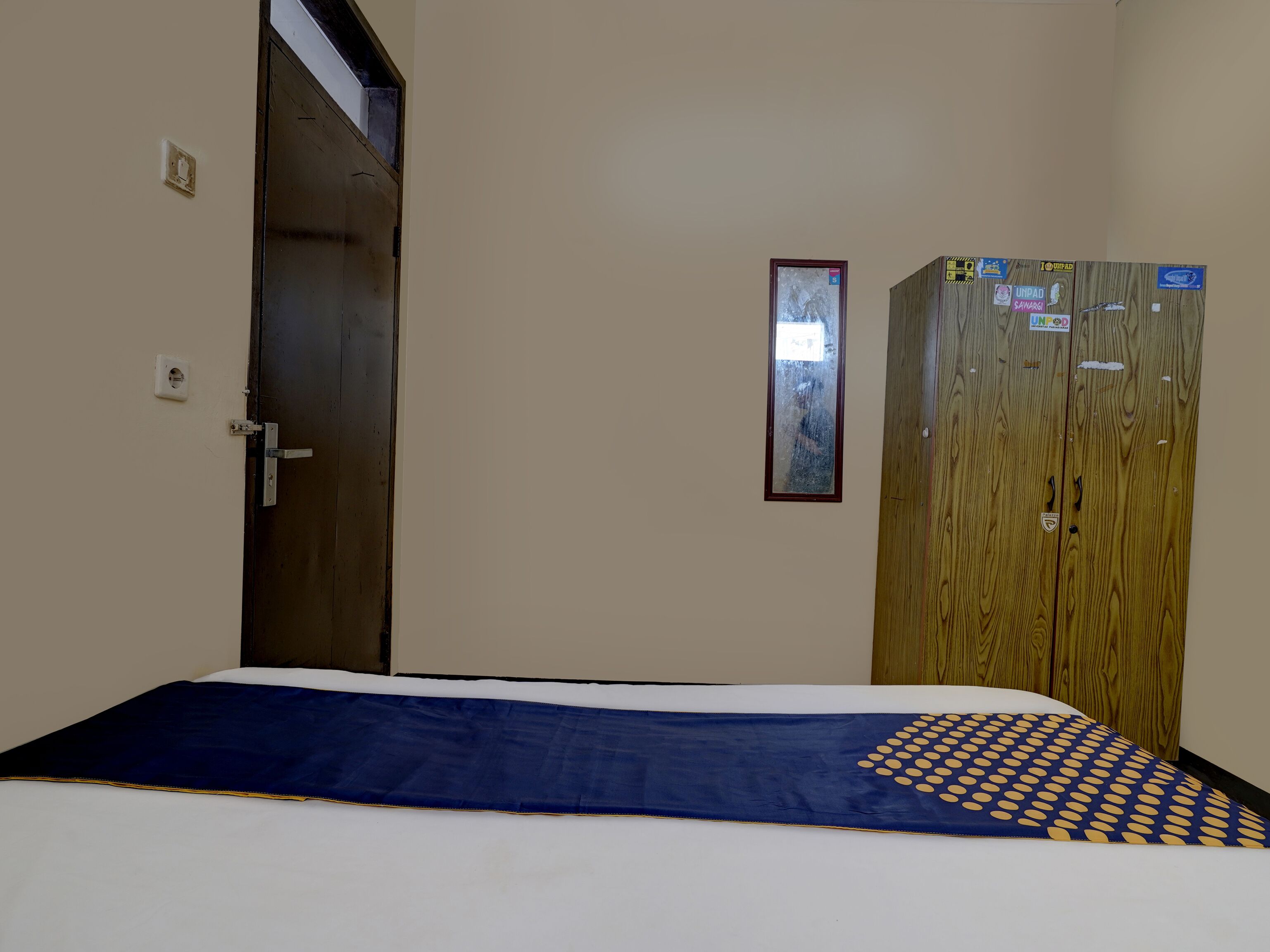 Um quarto com uma cama, um guarda-roupa de madeira e uma porta.