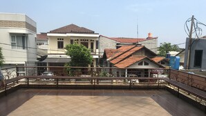 Terraço no telhado com piso de azulejos, guarda-corpo de metal e vista para edifícios próximos.