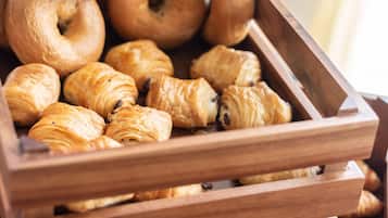 Uma caixa de madeira cheia de diferentes tipos de pastelaria, incluindo bagels e croissants.