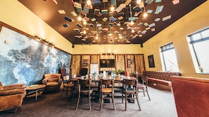 Uma sala de jantar com uma grande mesa de madeira, cadeiras de couro e luminárias pendentes.
