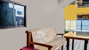 Um quarto com um banco de madeira, um banquinho e uma mesa com tampo de vidro.