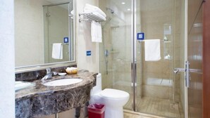 Casa de banho com cabine de duche envidraçada, lavatório com bancada de mármore e sanita.