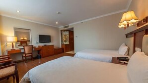Quarto de hotel com duas camas, uma escrivaninha, uma cadeira, uma televisão e um abajur.