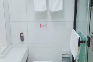 Casa de banho com sanita, secador de mãos e suporte para toalhas.