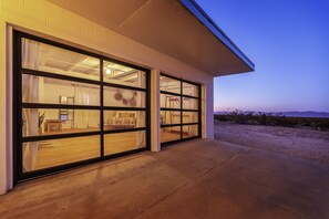 Um edifício moderno com grandes portas de vidro que dão acesso a um espaço interior com área de refeições e cozinha.