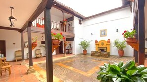 Um pátio com piso de azulejos, móveis de madeira e plantas em vasos.
