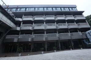 Um edifício com várias andares, sacadas, entrada coberta e plantas em vasos.