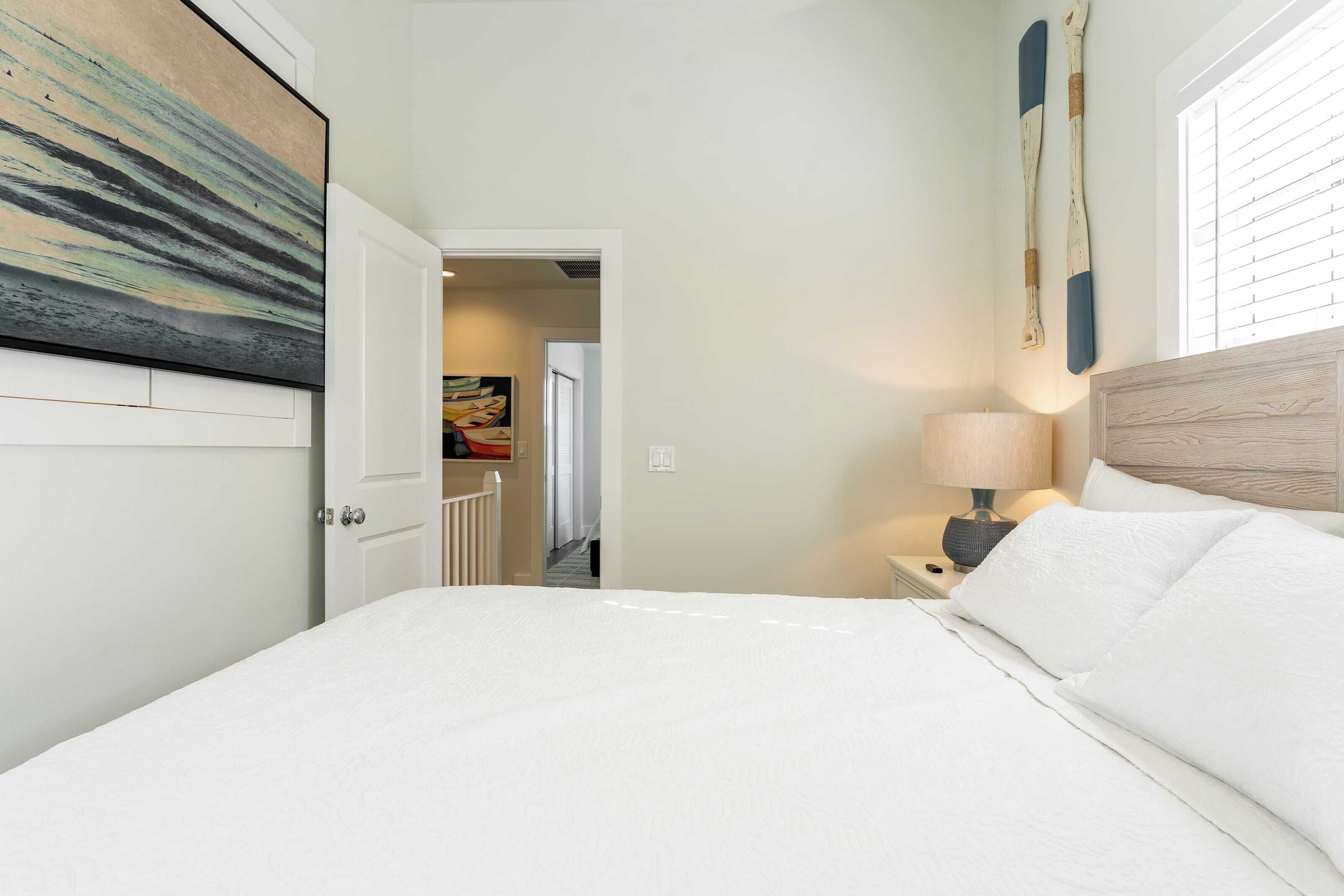 Um quarto com uma cama, uma mesinha de cabeceira com abajur e um quadro na parede.