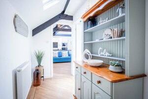 Uma cozinha com bancada de madeira, radiador branco e sofá azul ao fundo.