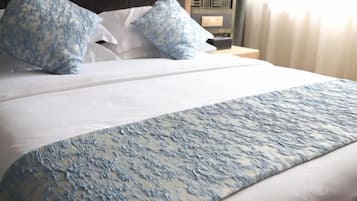 Uma cama bem arrumada com um cobre-leito estampado e dois travesseiros.