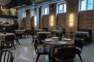 Um restaurante com paredes de tijolo, mesas redondas e cadeiras.