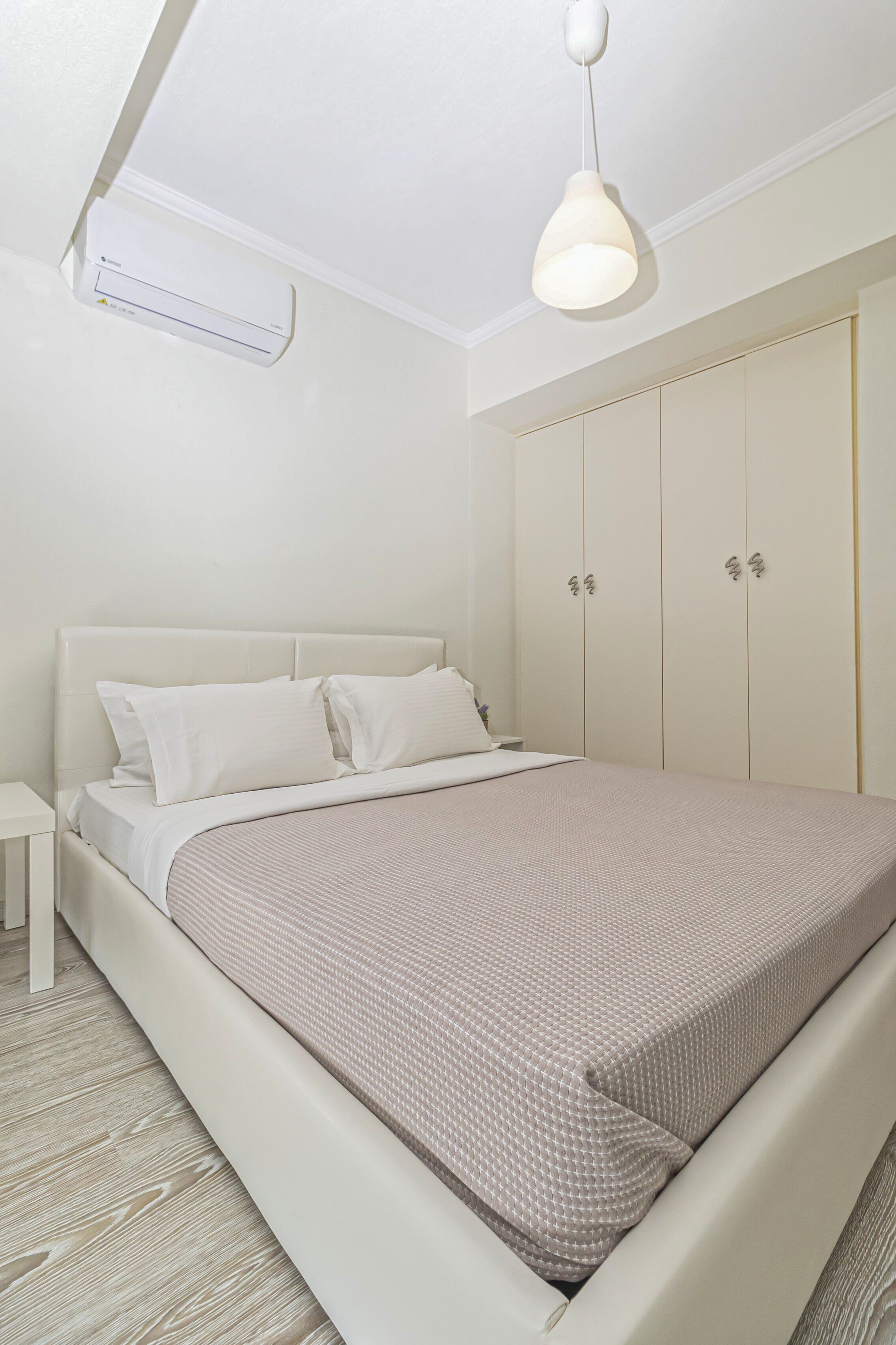 Quarto com cama, mesa de cabeceira, guarda-roupa e luz no teto.