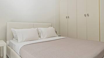 Quarto com cama, mesa de cabeceira, guarda-roupa e luz no teto.