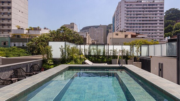 Piscina no terraço com vista para edifícios ao redor.